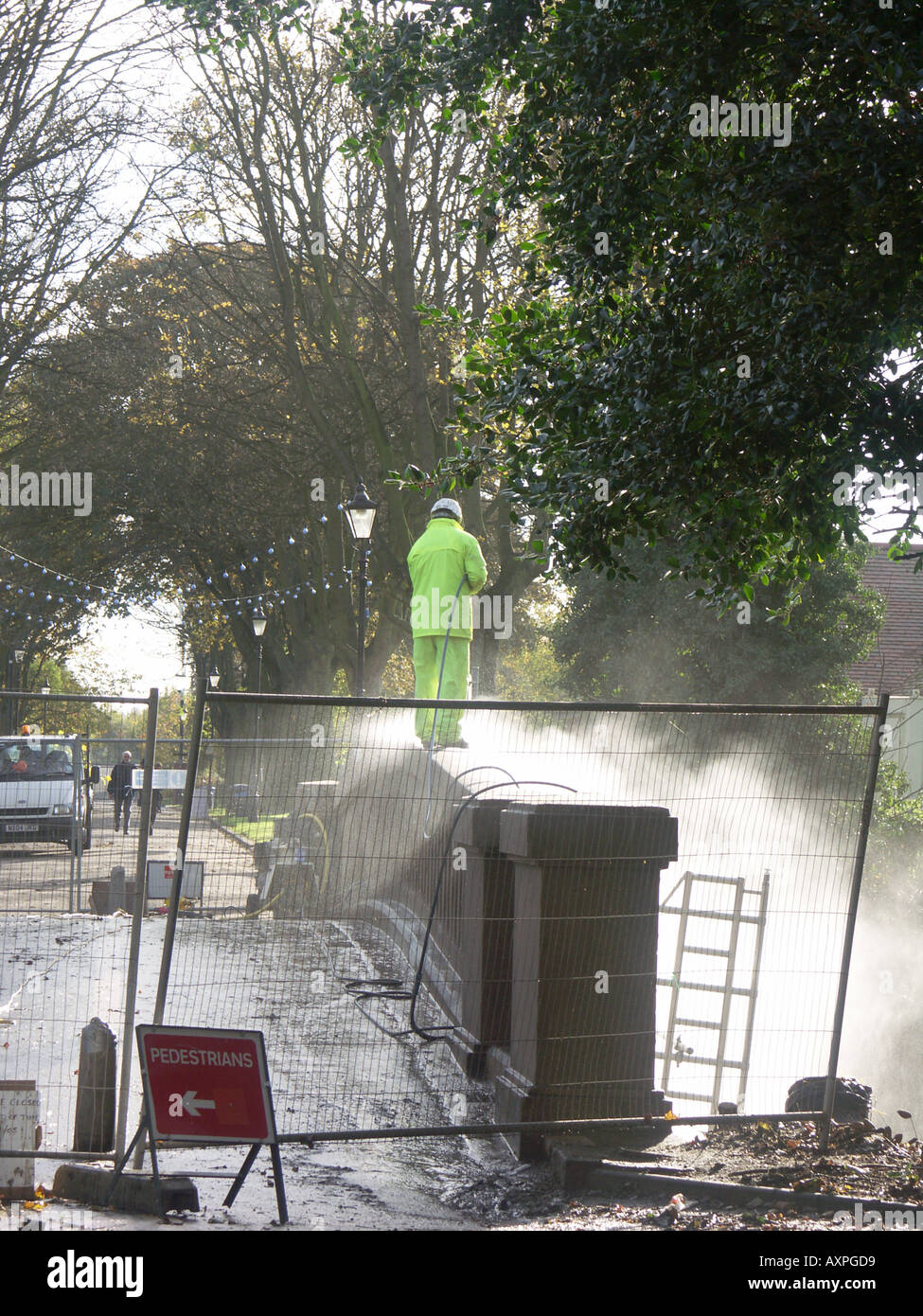 A workman cleans an old precast concrete bridge with a high pressure ...