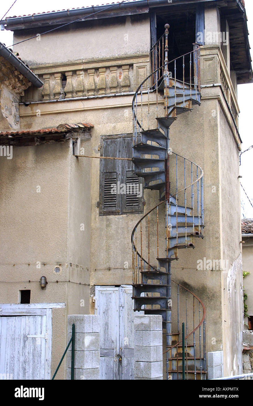 Spiral metal staircase, Grey window shutters outdoors. Vertical format ...