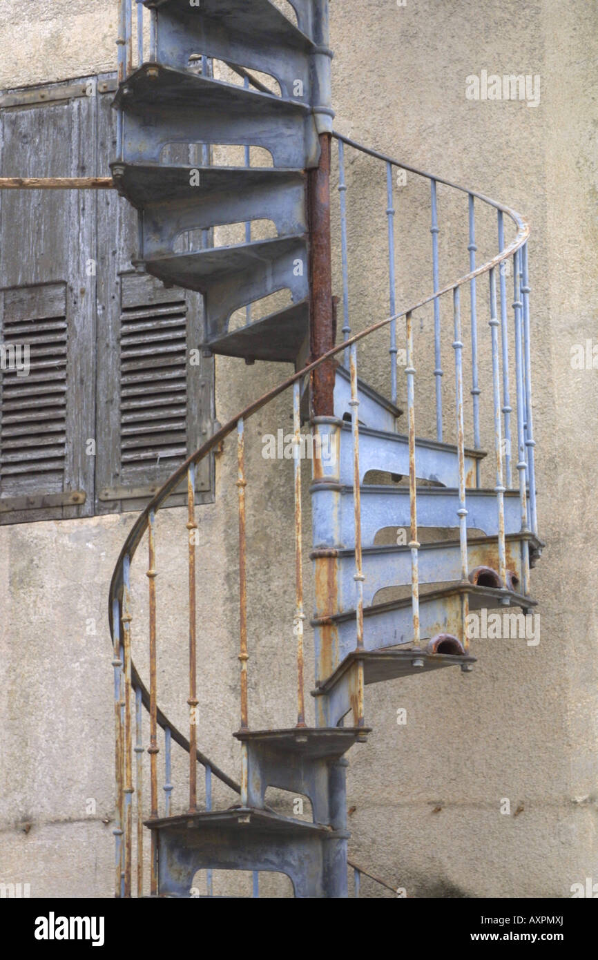 Spiral metal staircase, Grey window shutters outdoors. Vertical format ...