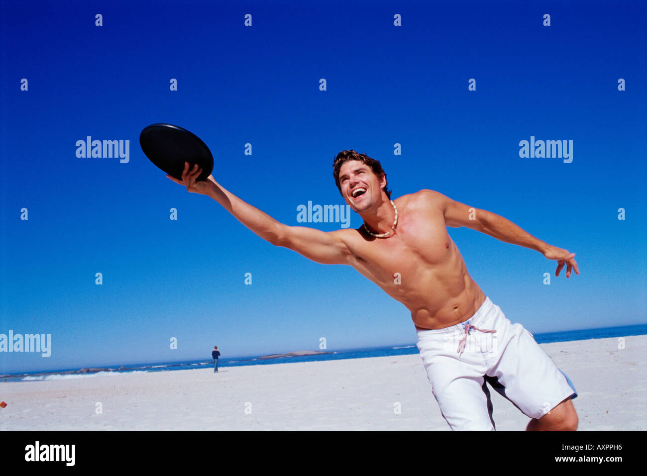 Young man playing frisbee on the beach Stock Photo - Alamy
