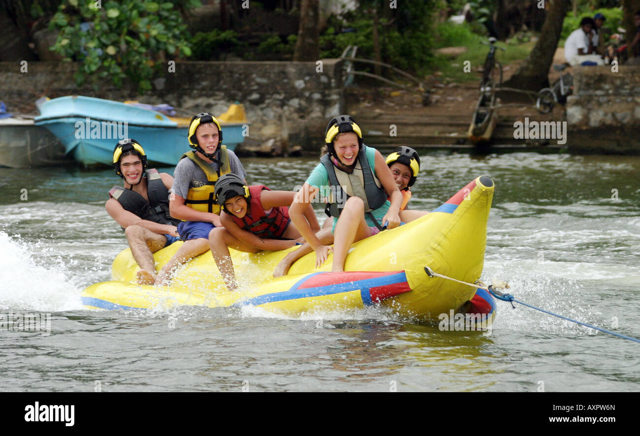 Five teenagers having fun on holiday riding on a banana boat, Bentota ...