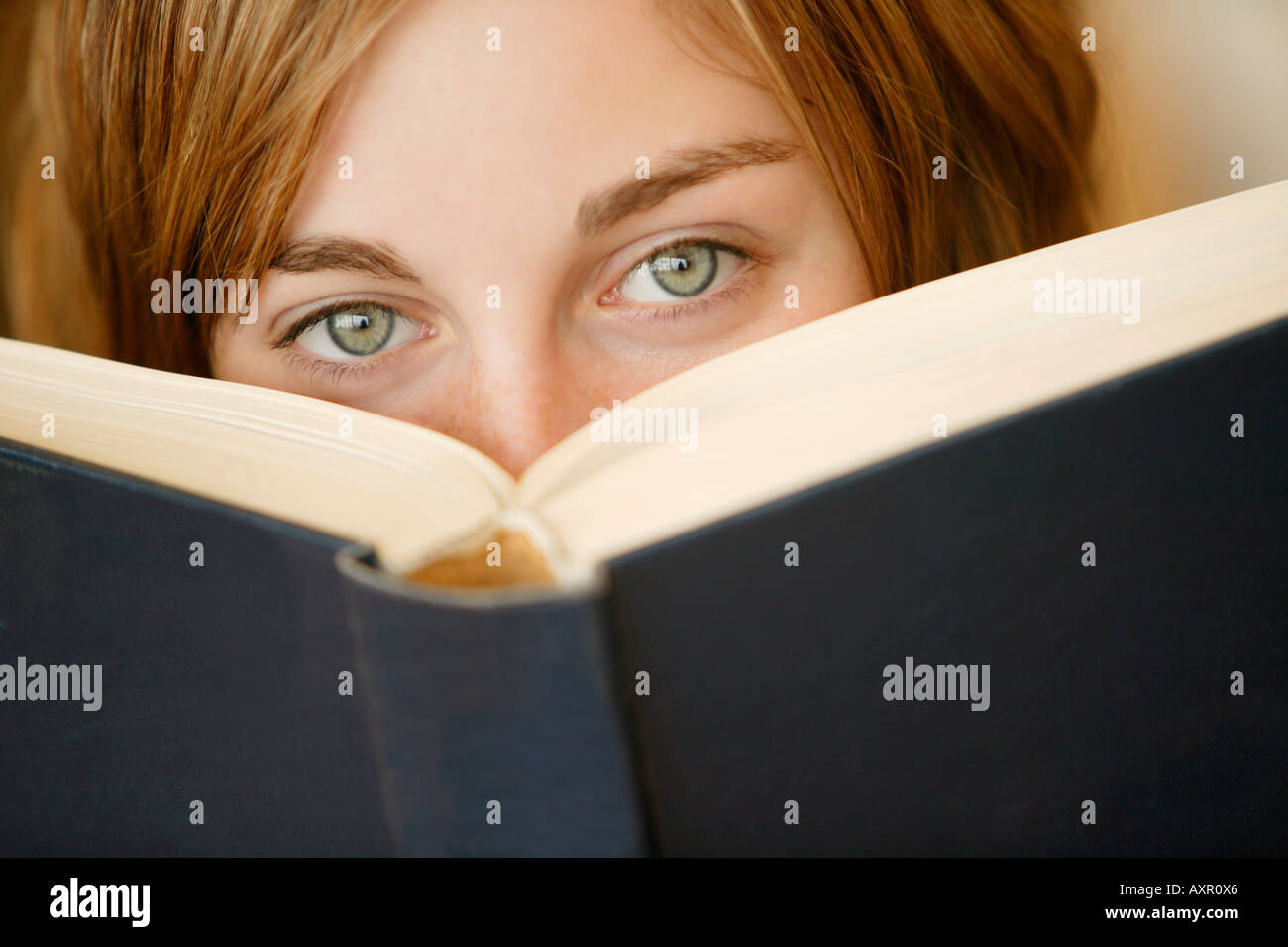 Young girl looking over book Stock Photo - Alamy