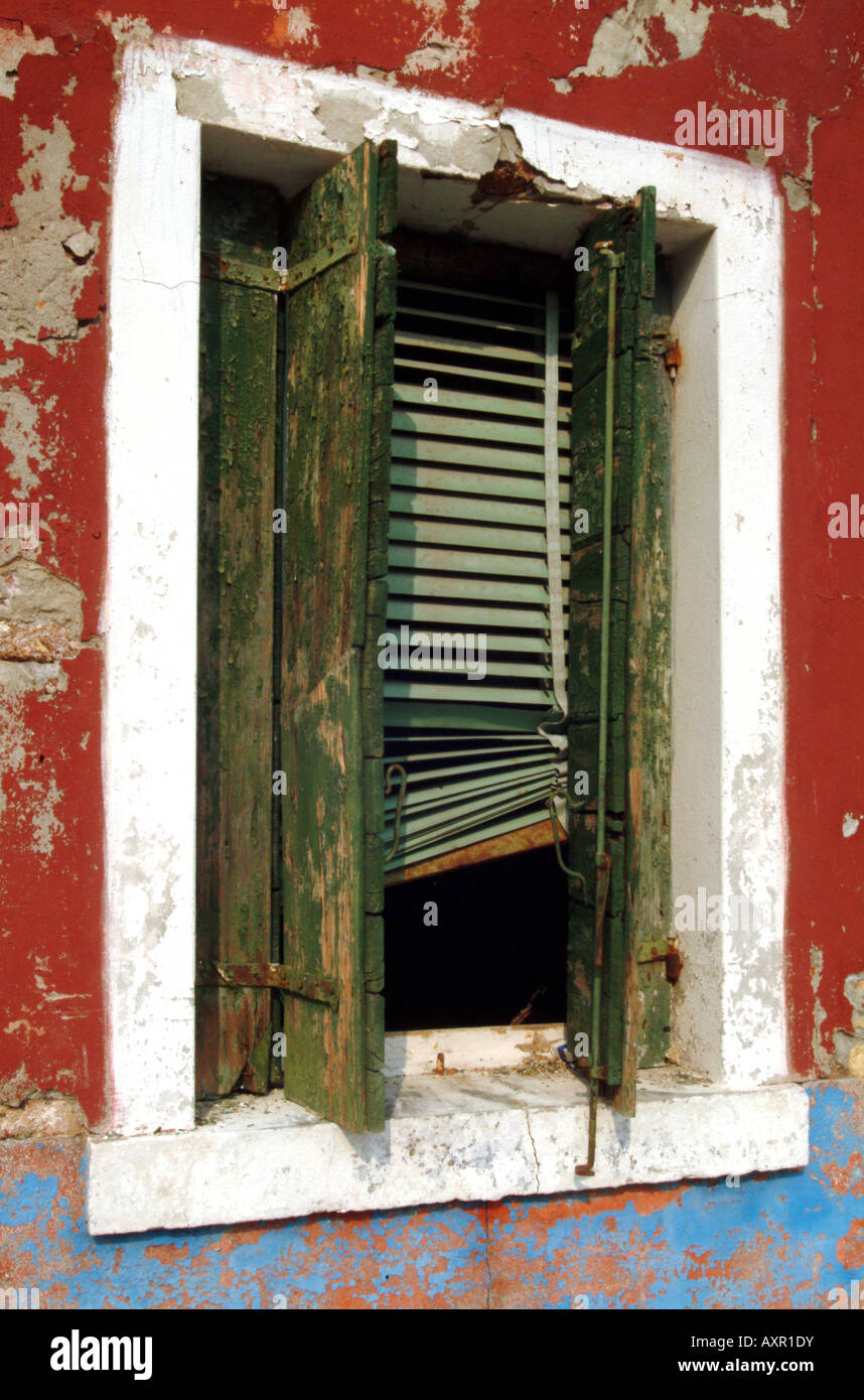Half opened weathered shuttered window with broken venetian blind on a ...