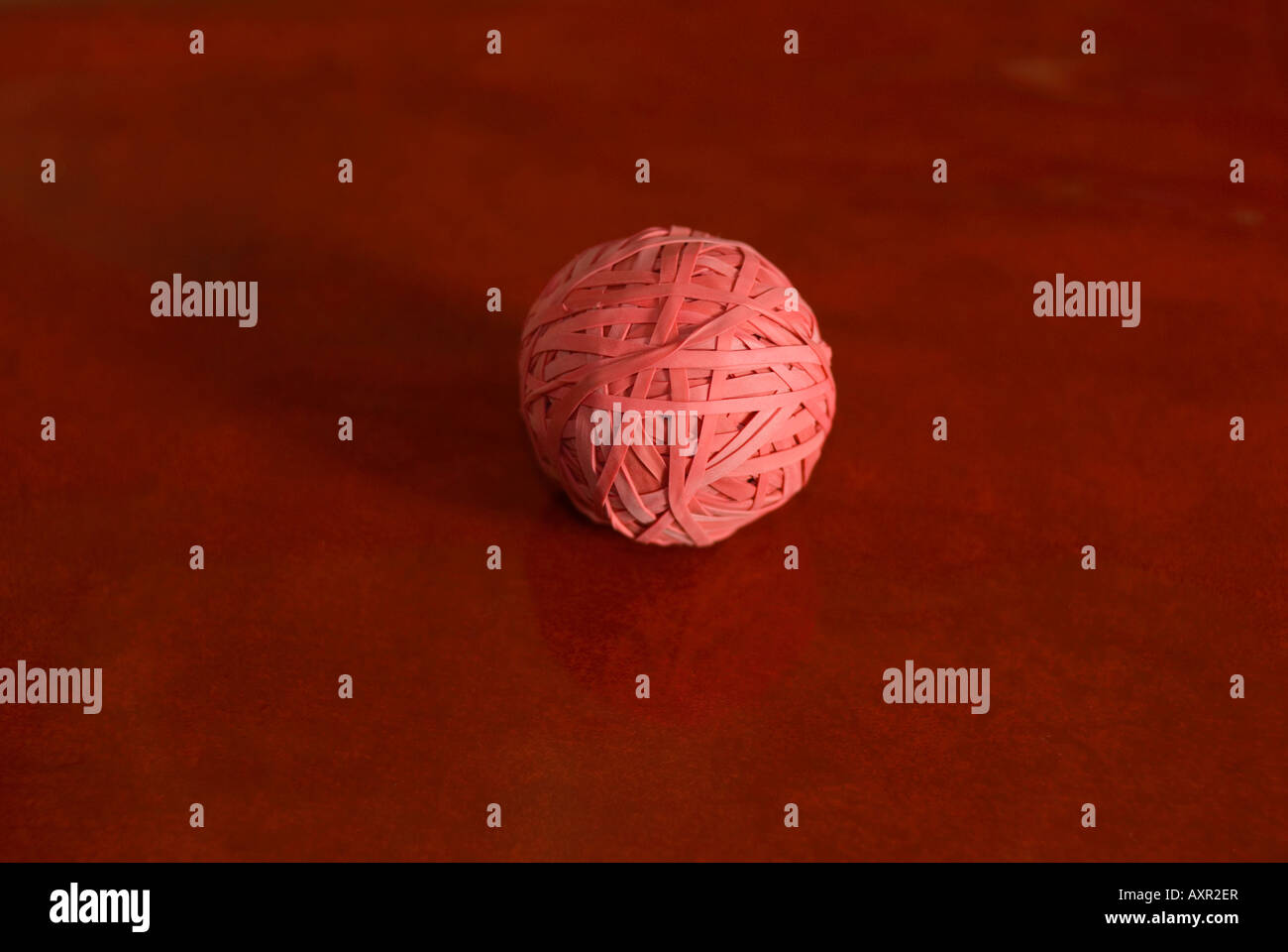 A ball made of red rubber bands on a red tablecloth Stock Photo - Alamy