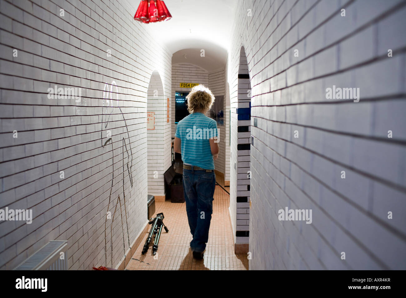 rear view of man walking through a passage made from white bricks and a ...