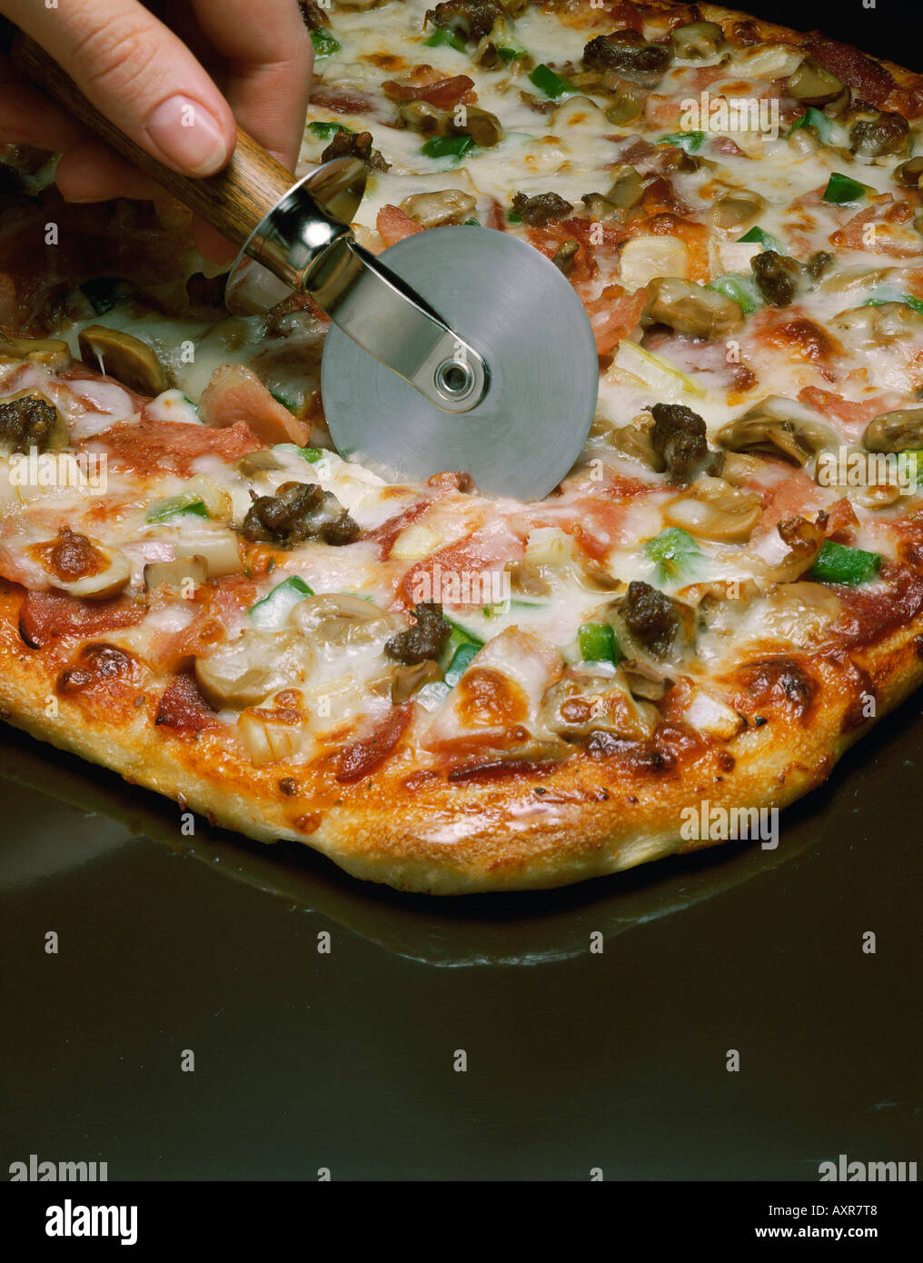 Person's hand cutting pizza with a pizza cutter Stock Photo - Alamy