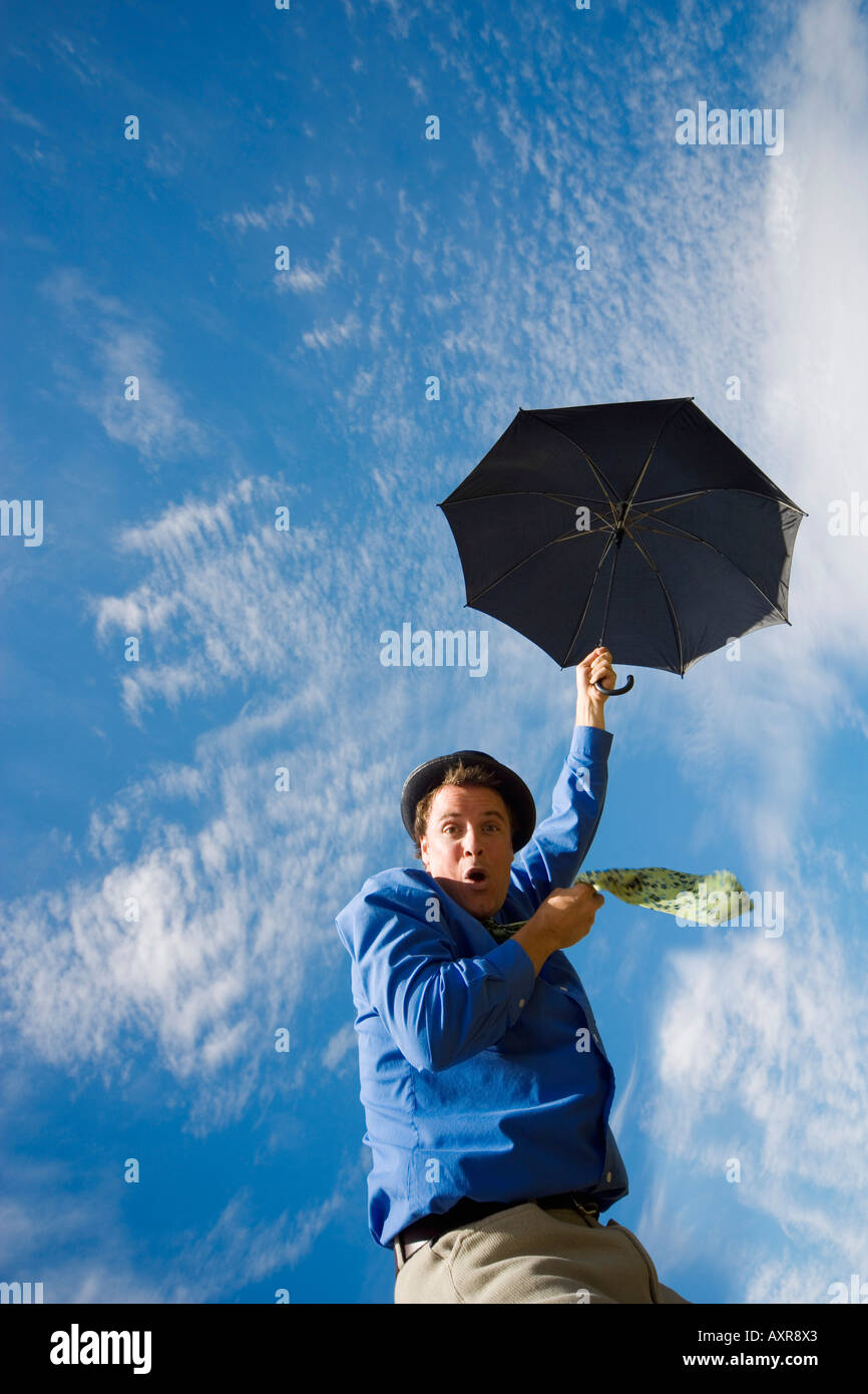 Man holding umbrella floating up into sky Stock Photo - Alamy