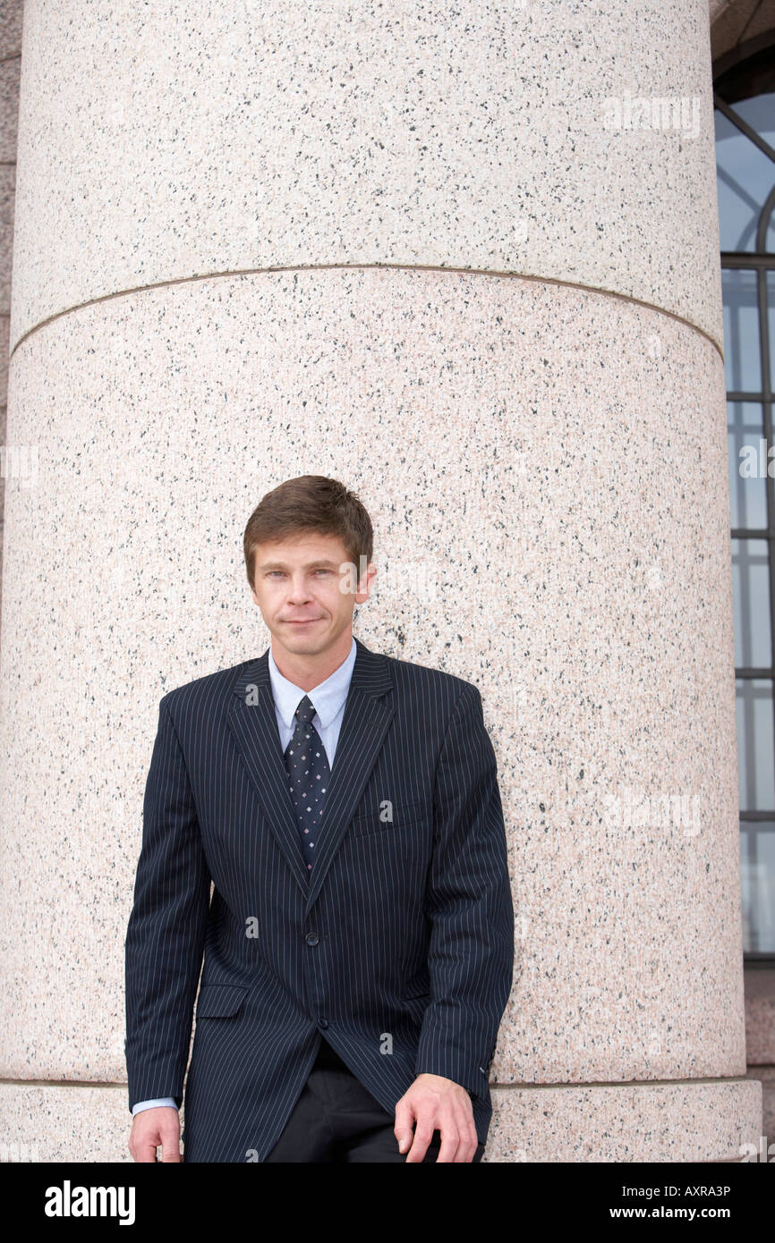 Man standing by pillar of building Stock Photo - Alamy