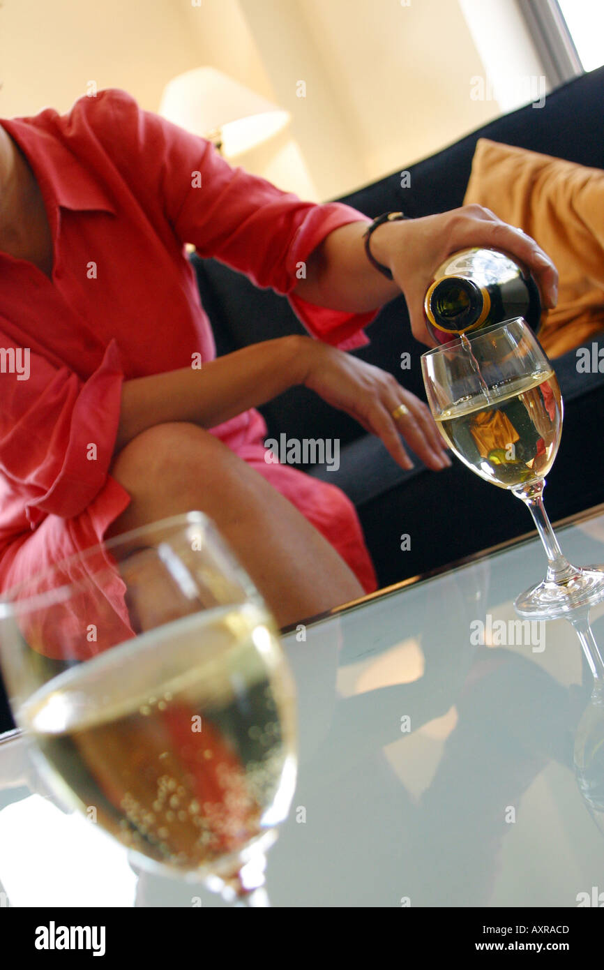Lifestyle photo in a cosmopolitan home of a woman pouring a glass of ...