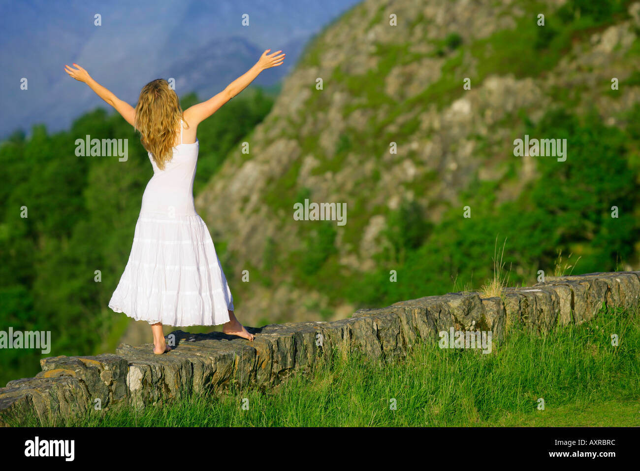 Woman balancing on rock wall ledge Stock Photo - Alamy