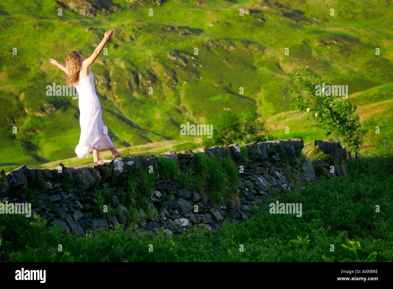 Woman balancing on rock wall ledge Stock Photo - Alamy