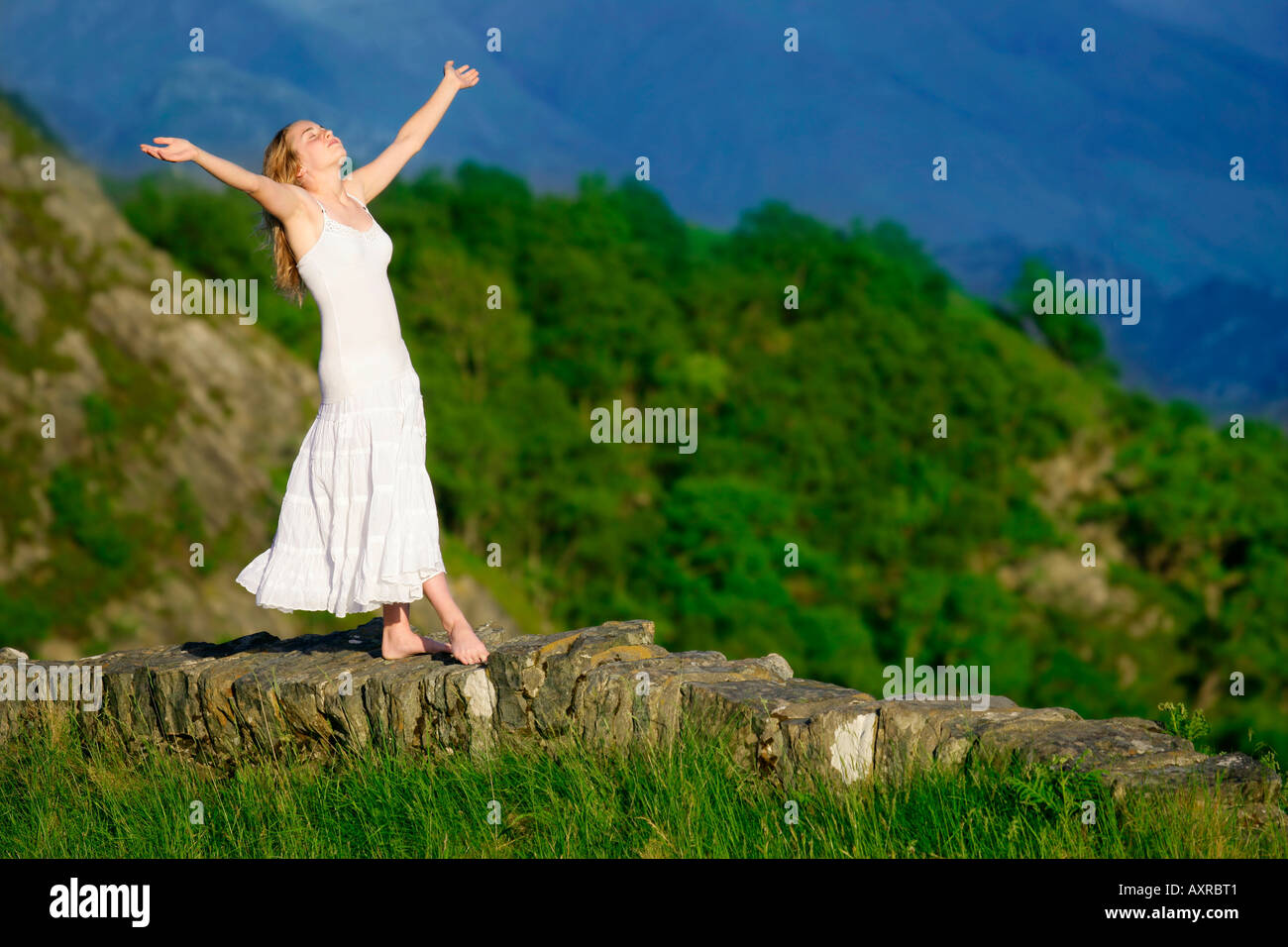 Woman balancing on rock wall ledge with eyes closed Stock Photo - Alamy