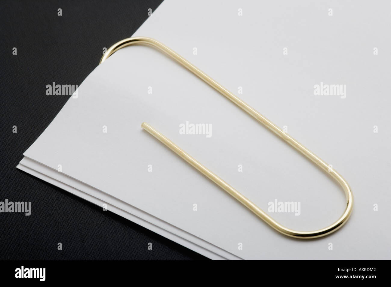 White paper clipped with gold paper clip Stock Photo - Alamy