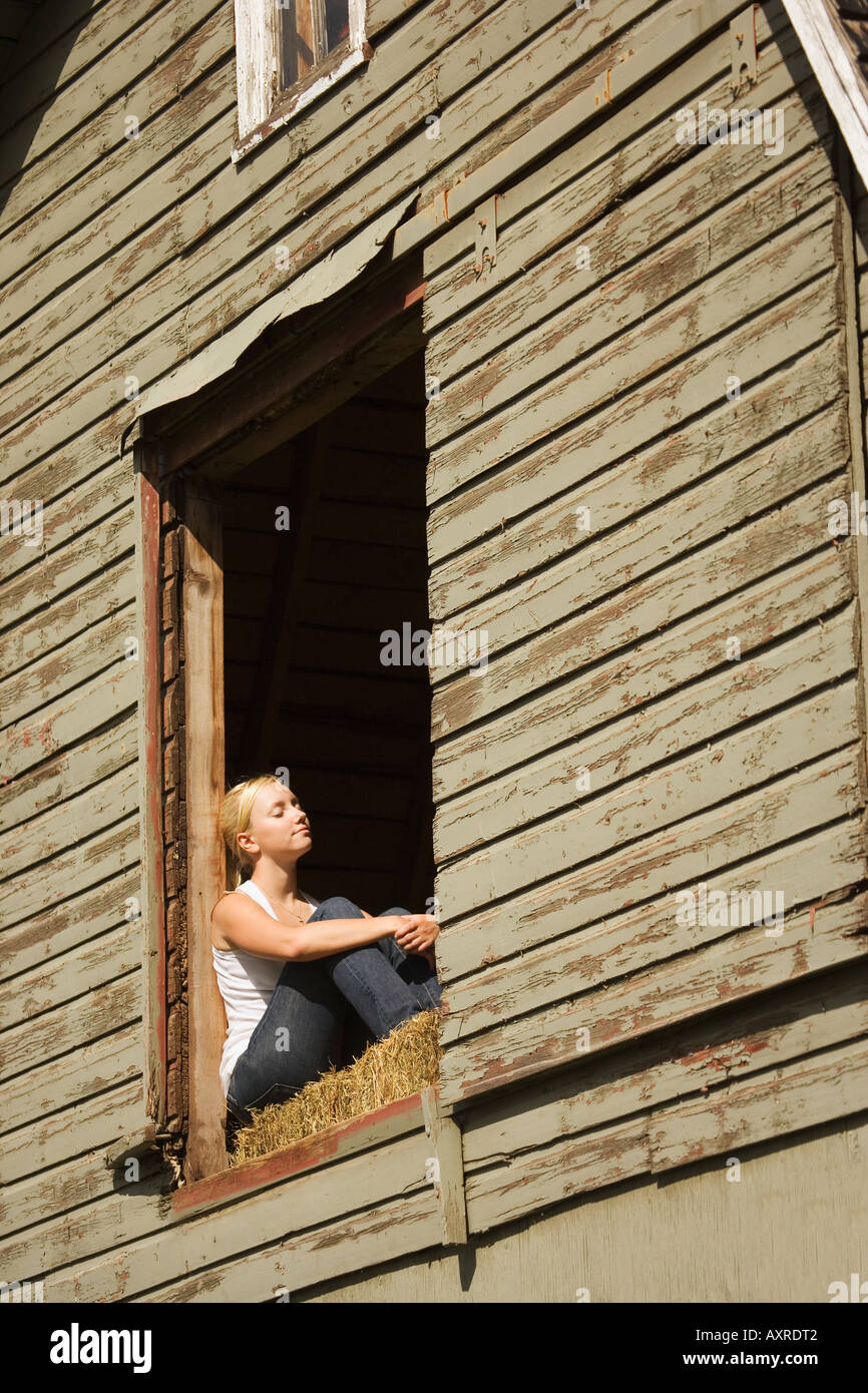 Woman sitting in a barn loft Stock Photo - Alamy