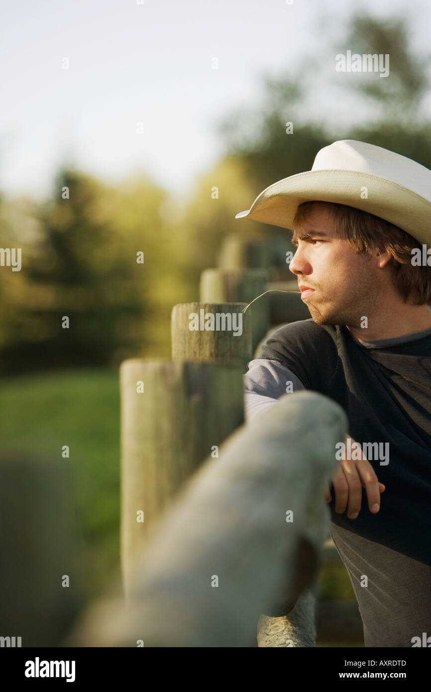 Young cowboy leaning on corral Stock Photo - Alamy