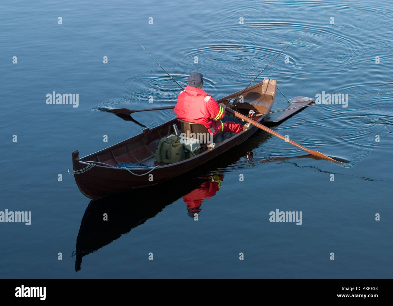 Fisherman trolling using a traditional wooden rowboat / skiff at River ...