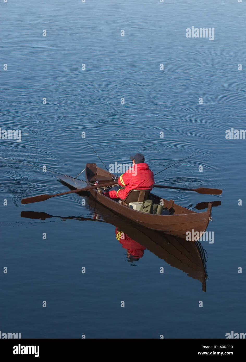 Fisherman rowing and trolling using a traditional wooden rowboat ...