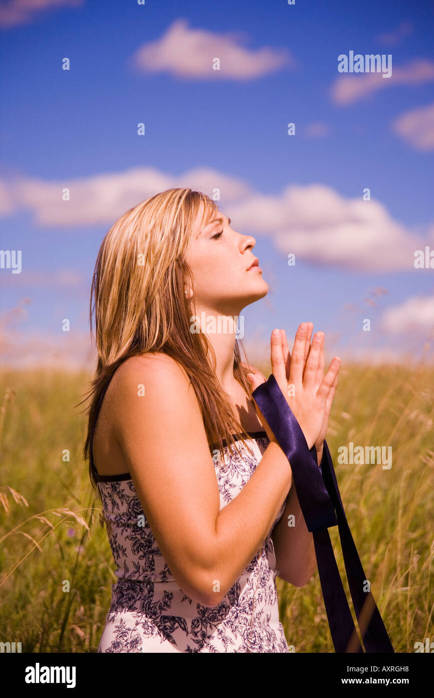 Woman praying in a field Stock Photo - Alamy