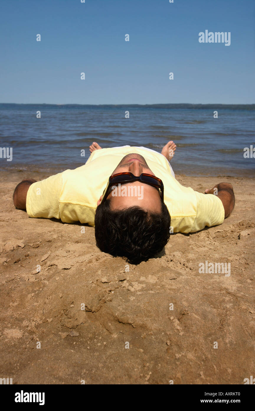Man lying on beach Stock Photo - Alamy