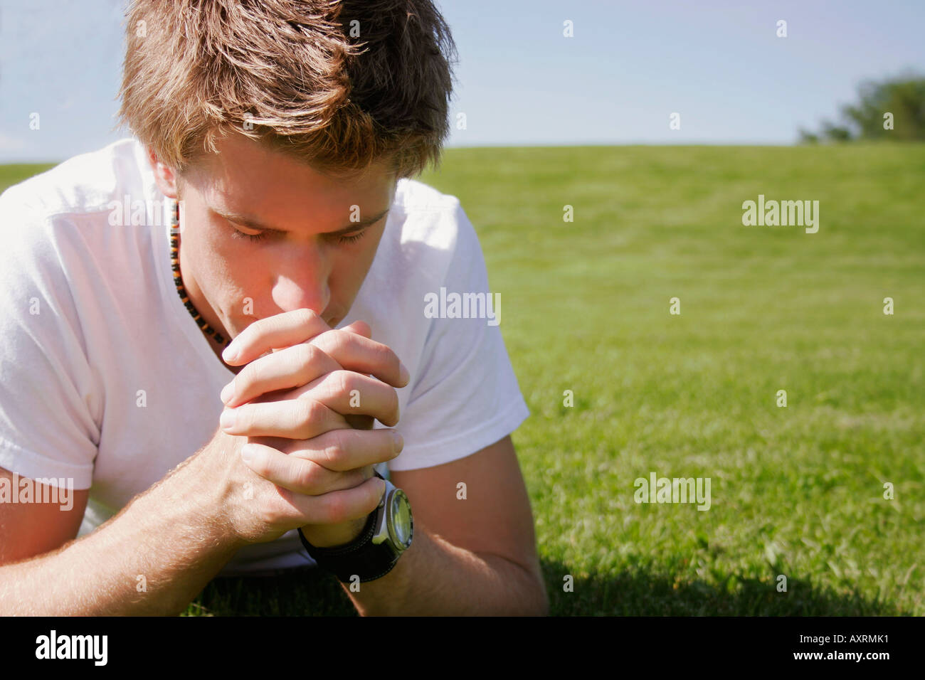 Young man praying outside Stock Photo - Alamy