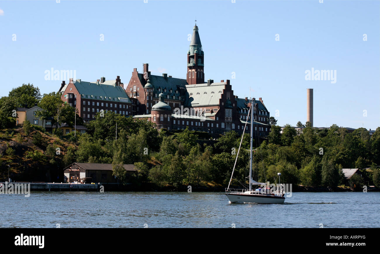A large building with copper roof juts from the trees. Sailboat in the ...
