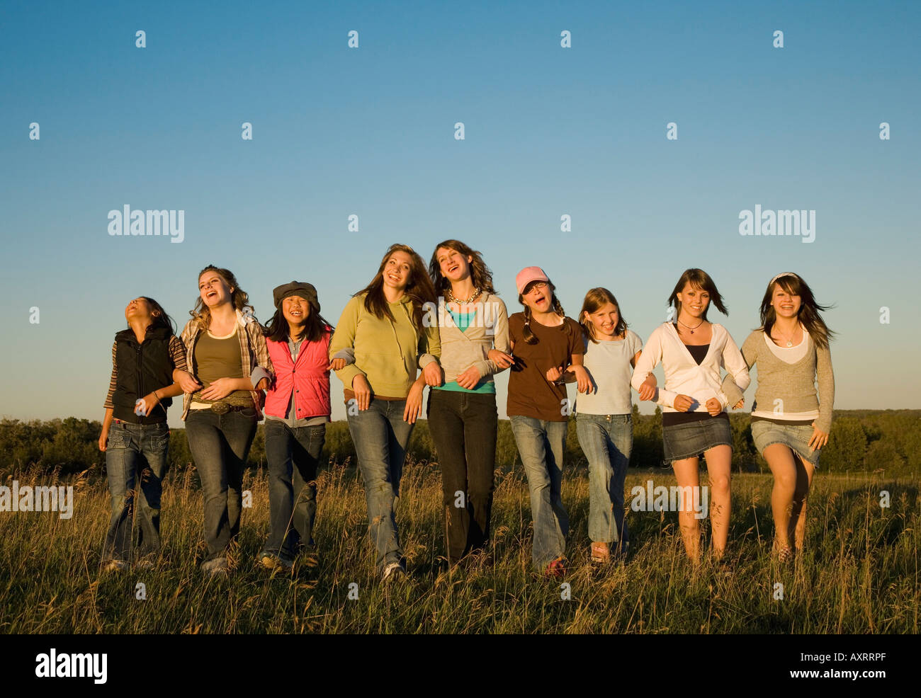 Girls and young women arm-in-arm in field Stock Photo - Alamy