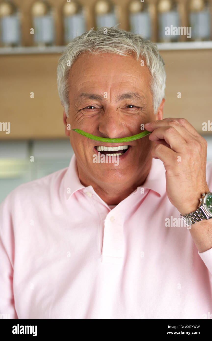 Gray-haired man holding a green bean under his nose, close-up Stock ...