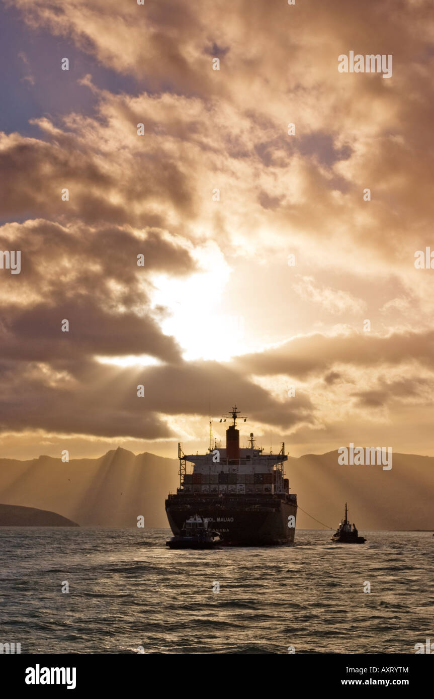 A container ship arrives into a setting sun at the port of Lyttelton ...