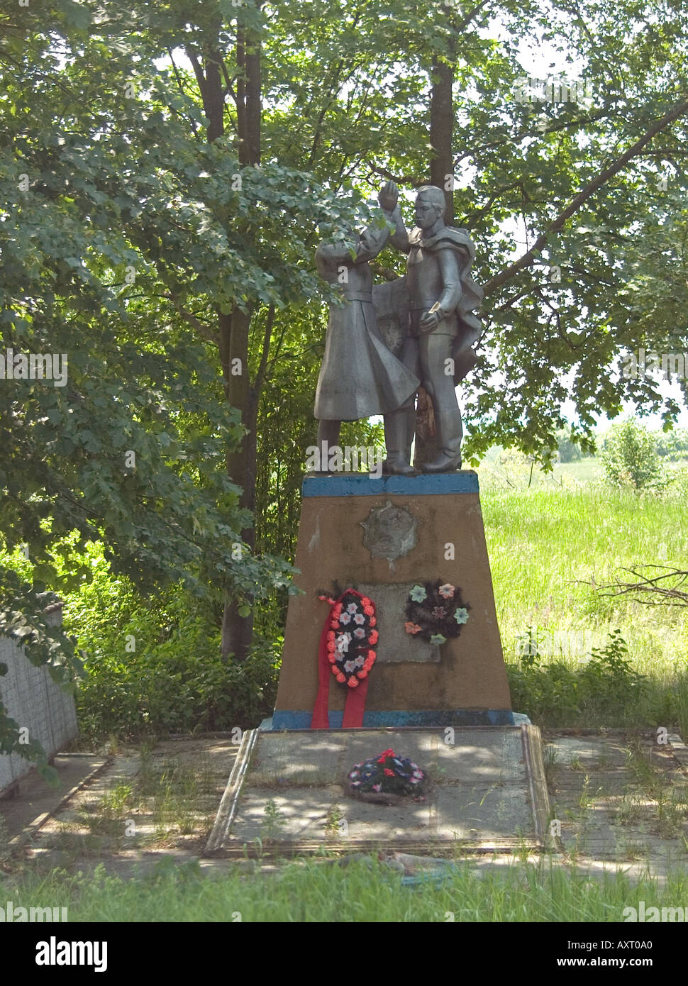 Commemorative statue featuring two figures on plinth, flower wreaths ...