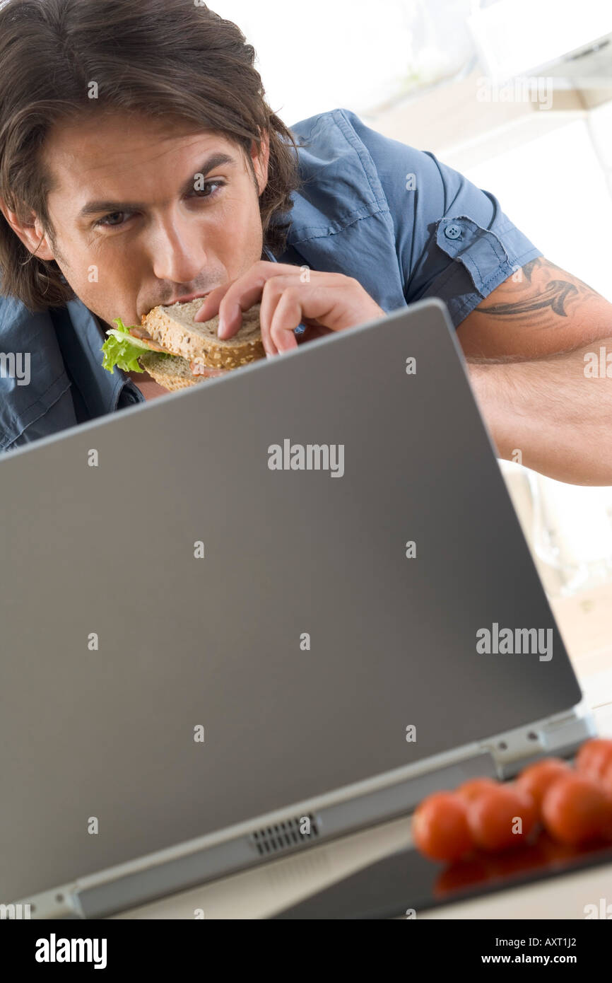 man eating sandwich next to laptop Stock Photo - Alamy