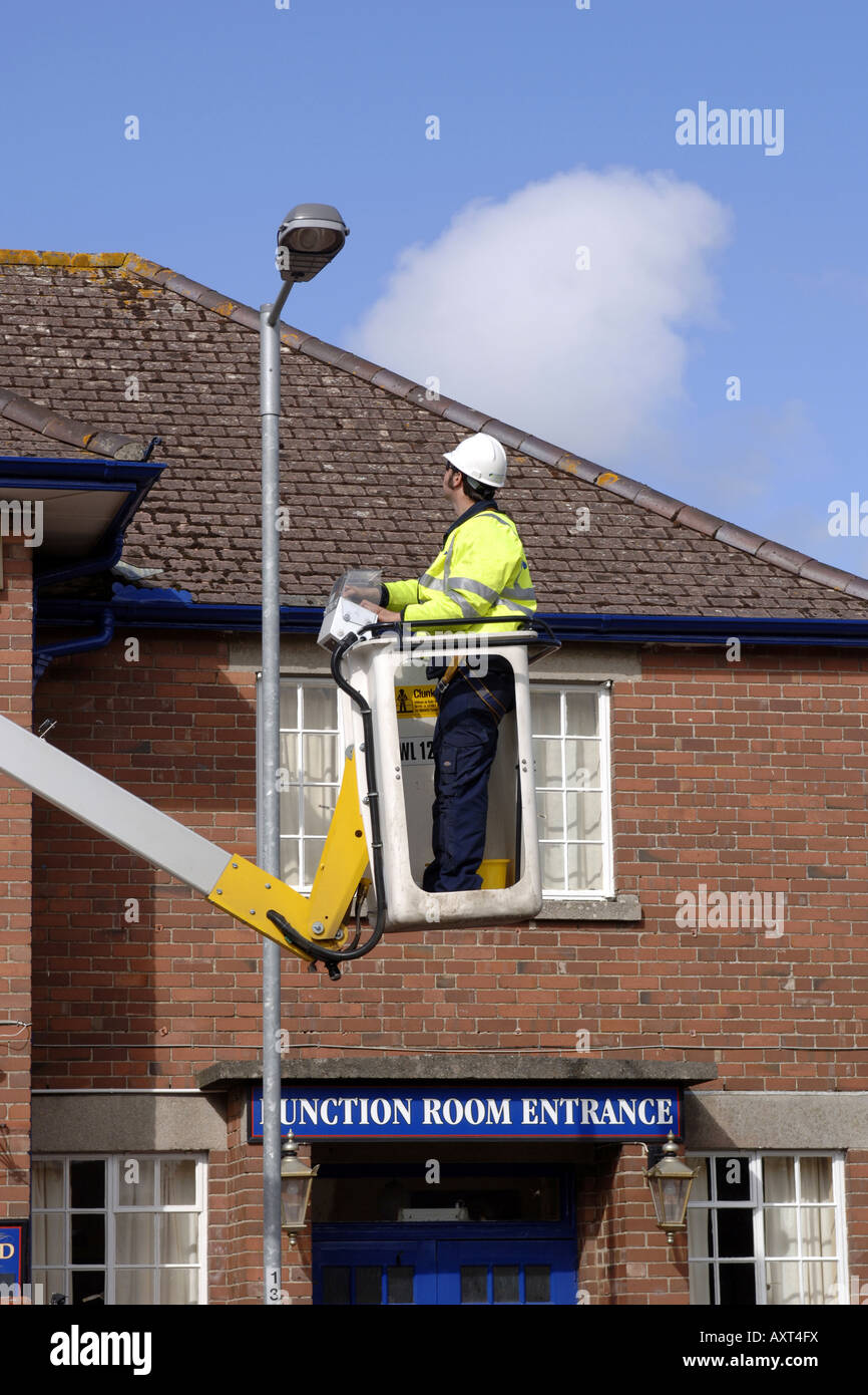 Adult male elecrician uses a mobile lift to gain access to a street ...