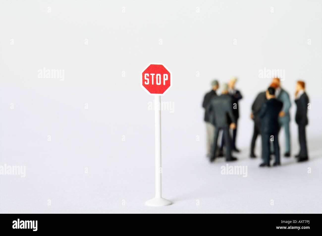 Group of businessmen figurines standing in circle, stop sign in ...