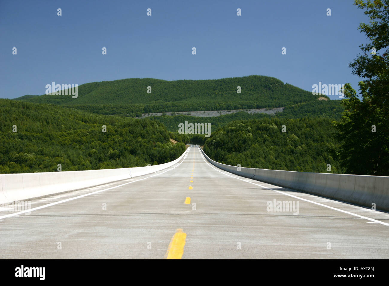 Looking straight down a concrete highway in the Cascades of Washington ...