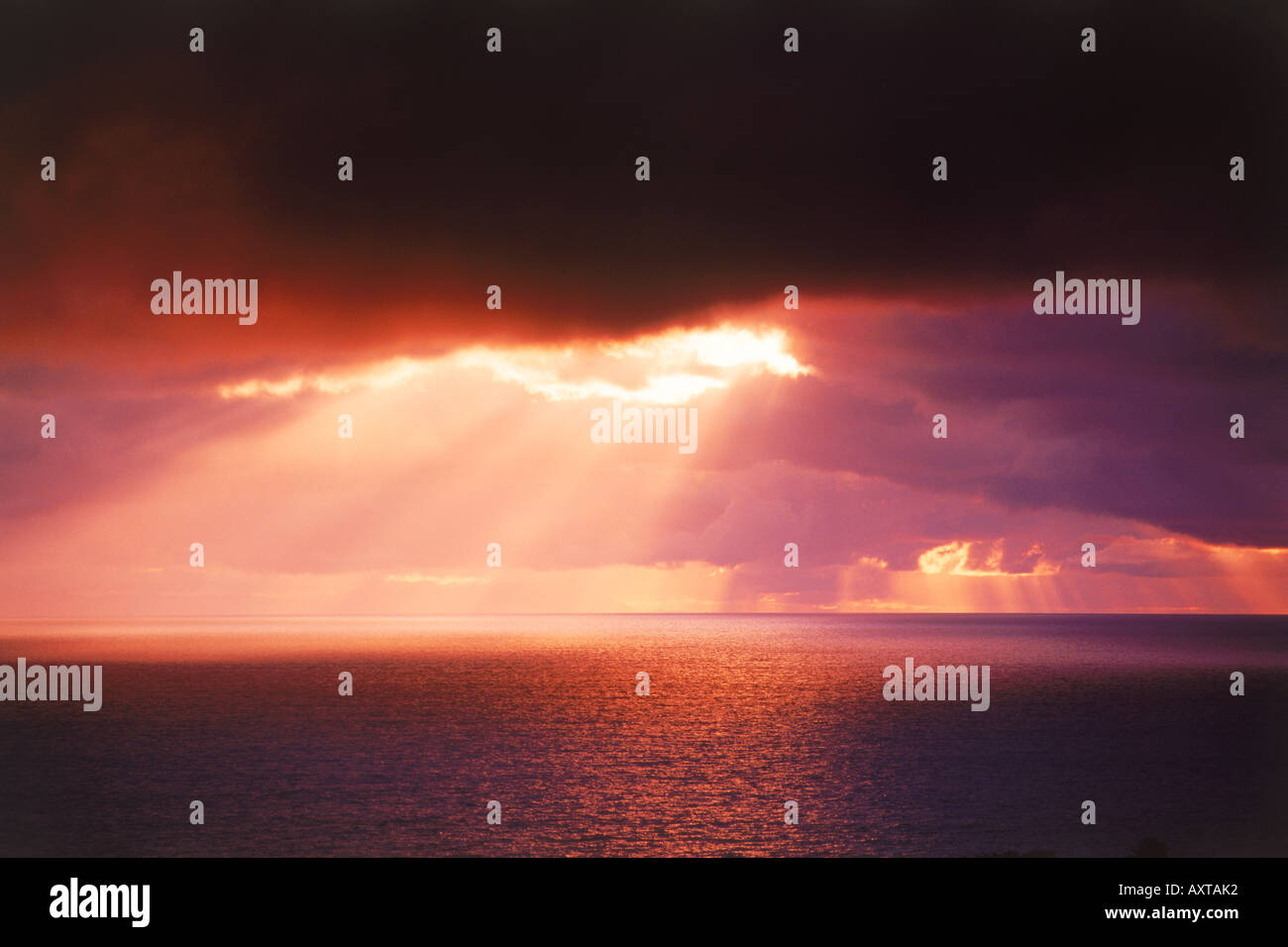 Sun rays bursting through cloudy skies over boundless ocean Stock Photo ...