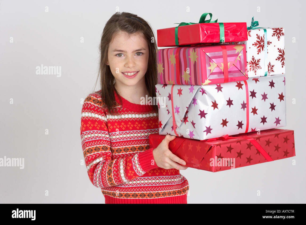 Girl carrying a stack of Christmas presents Stock Photo - Alamy