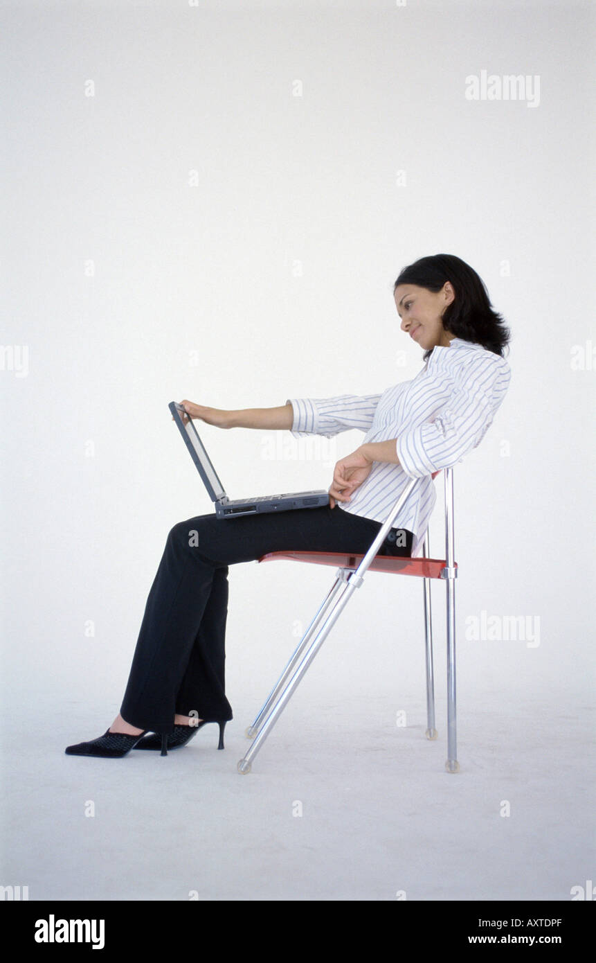 Side profile of a young woman sitting in a chair with a laptop on her ...