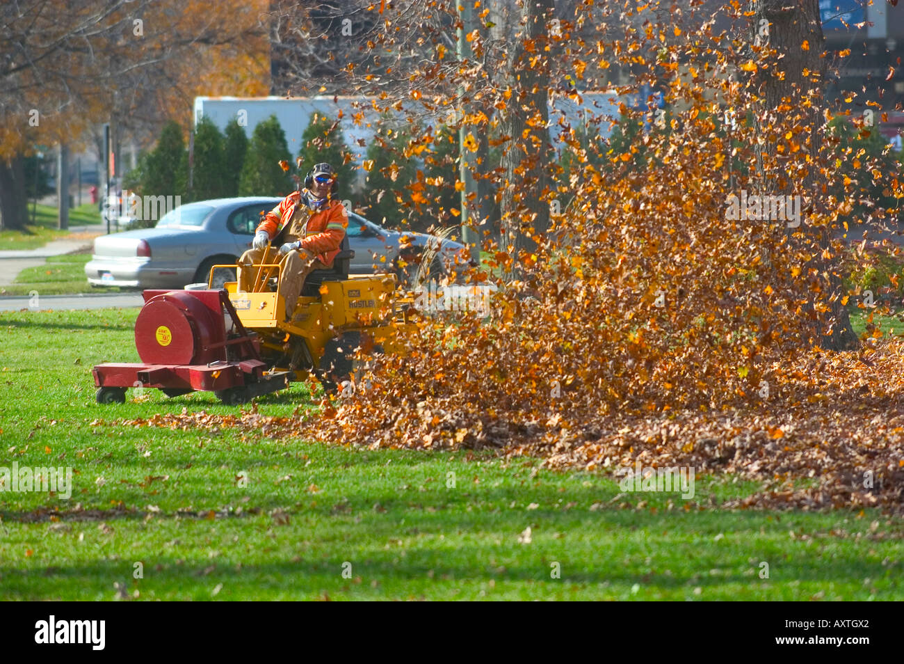 City works blow and clear fallen leaves from a city park during fall ...