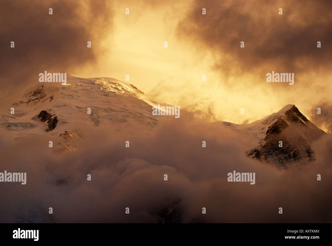 Last rays of setting sun with storm clouds closing in over snow capped ...