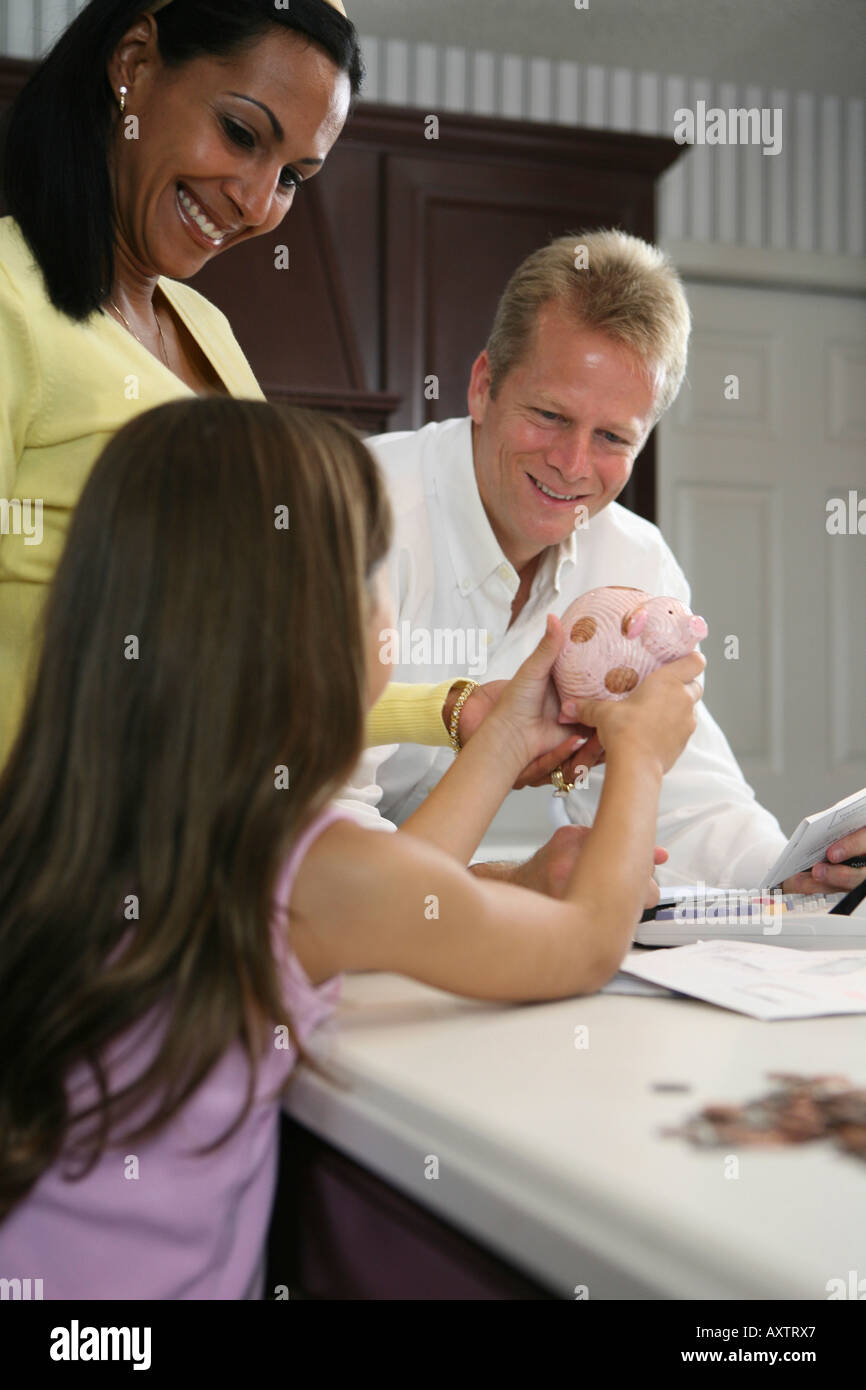 Side profile of a daughter showing a piggy bank to her parents Stock ...