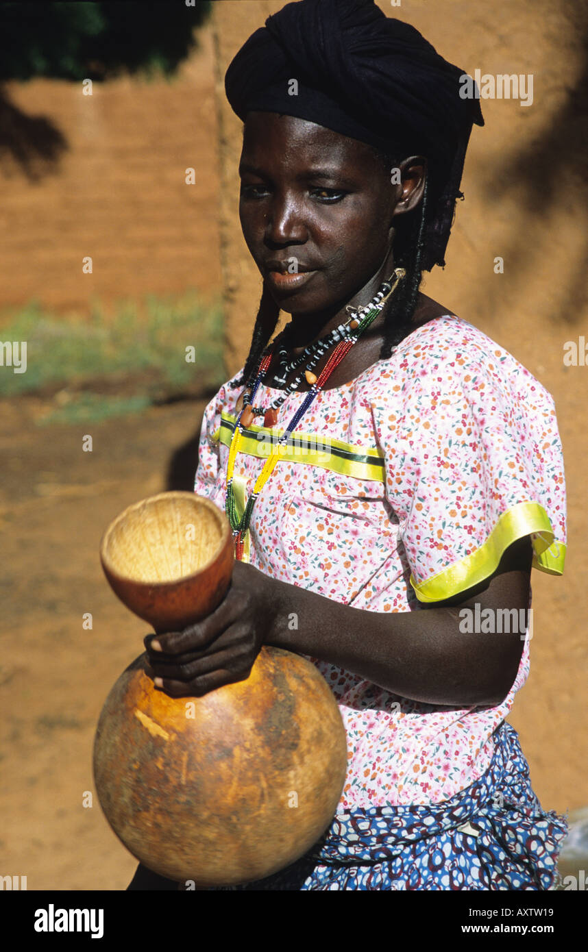 A portrait of an African woman carrying a traditional water pot, near ...