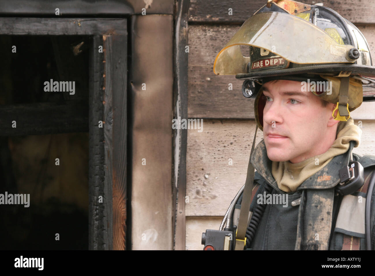 A firefighter standing in front of a burnt structure after a house fire ...