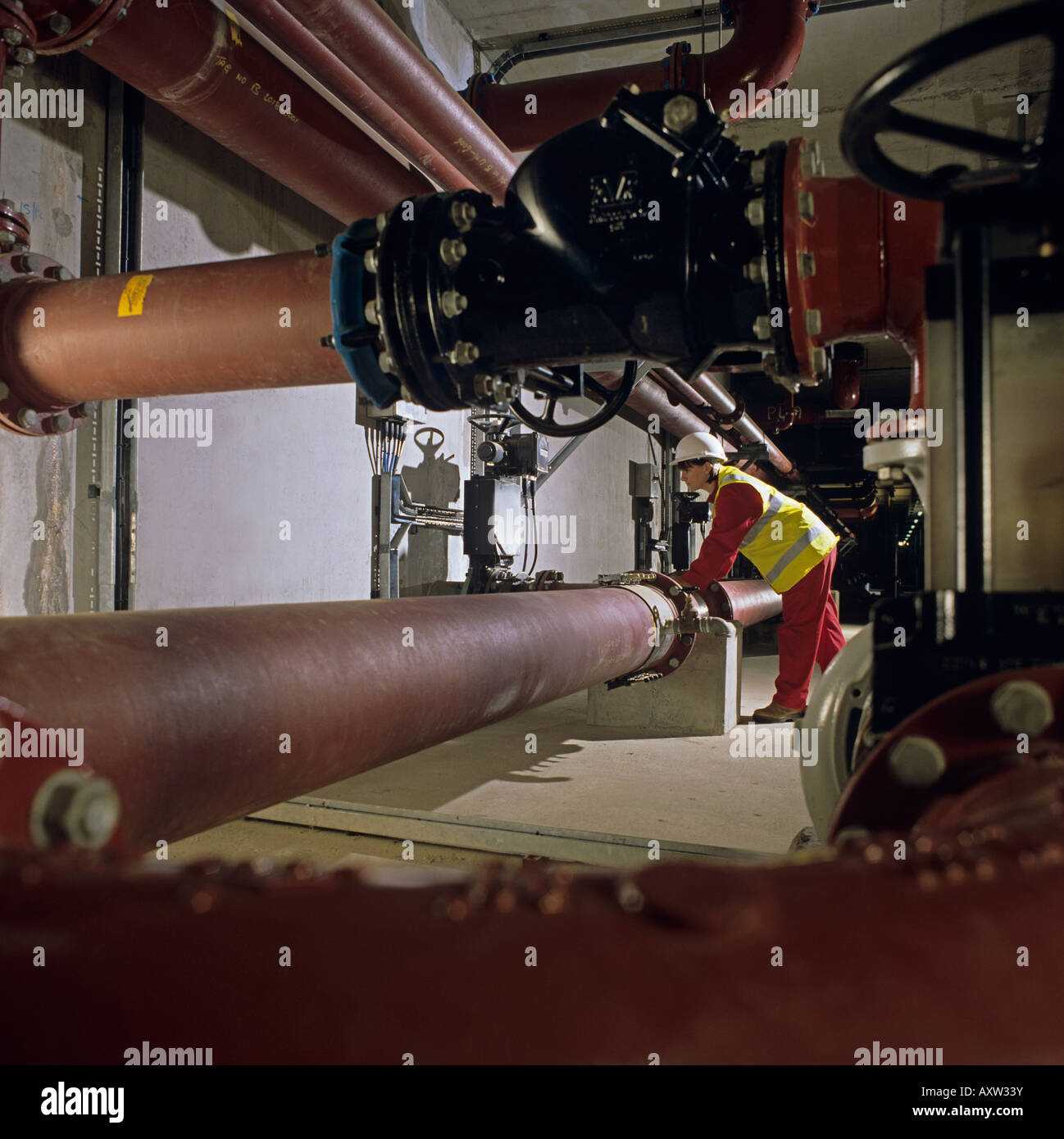 Operator adjusting water flow by turning valve inside water treatment ...