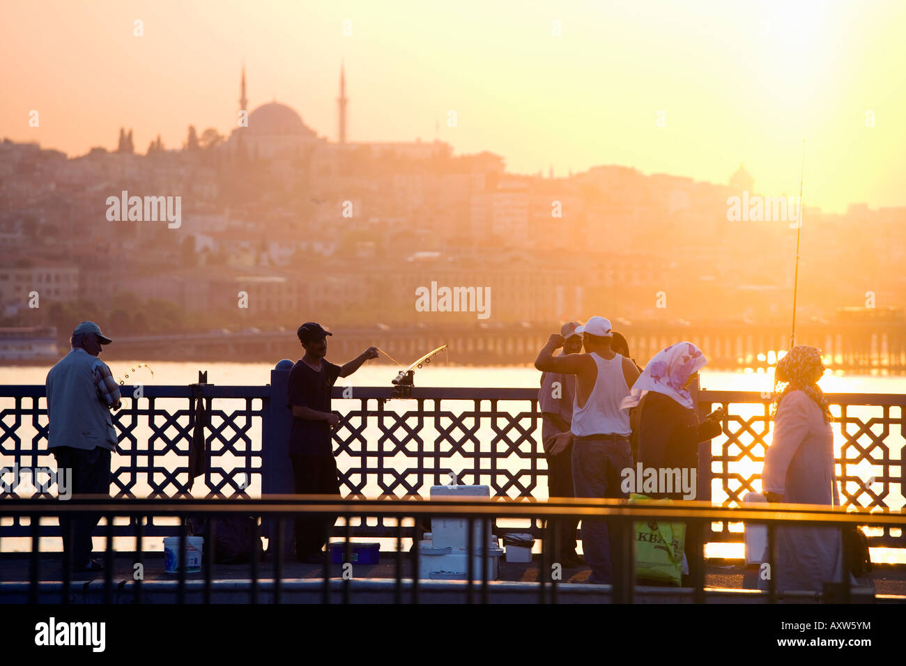 Istanbul, Marmara Region, Turkey; fishermen on Galata Bridge at sunset ...