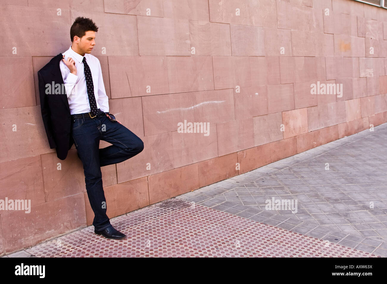 Lone businessman posing on wall Stock Photo - Alamy