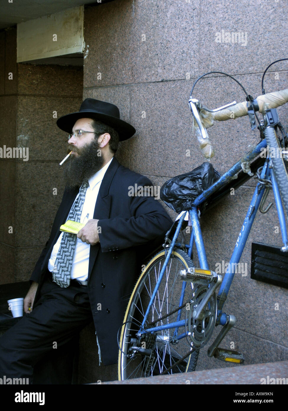 jew in traditional clothes smoking cigarette at entrance of a synagoge ...