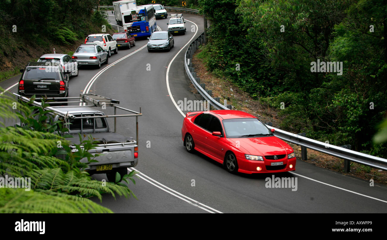 A late model red Holden saloon car on the S bend near Avalon beach ...