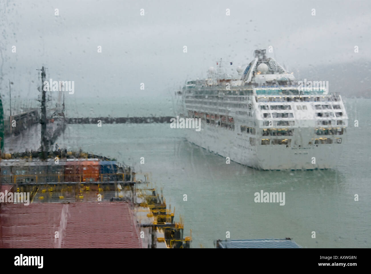 A cruise ship departs port in rain as viewed through a rain splashed ...