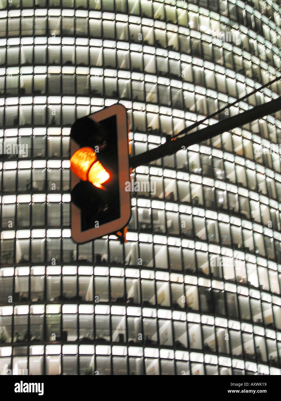 yellow traffic light in front of illuminated office buildings at dusk ...