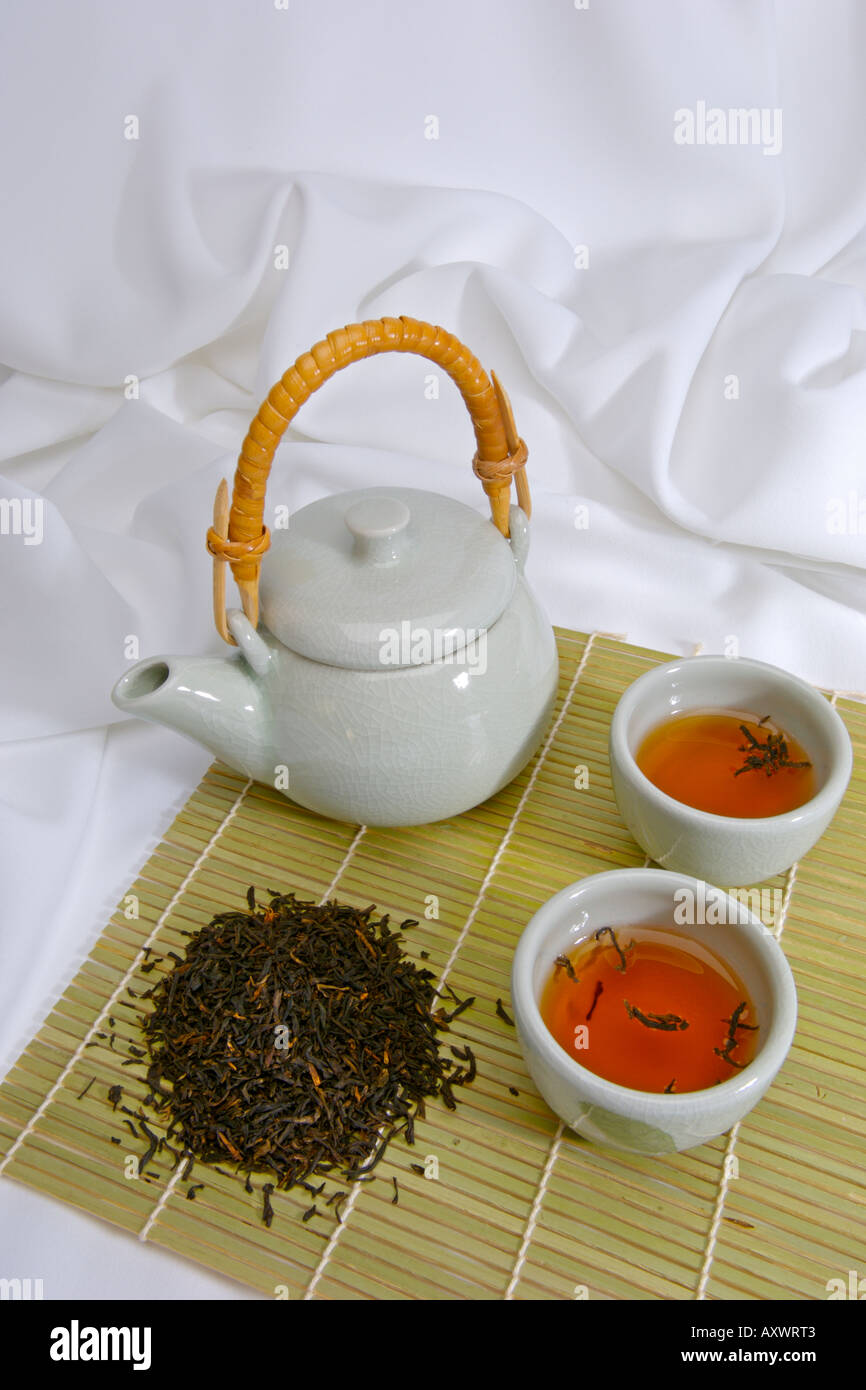 Green chinese teapot with tea cups and tea leaves ready to serve tea ...