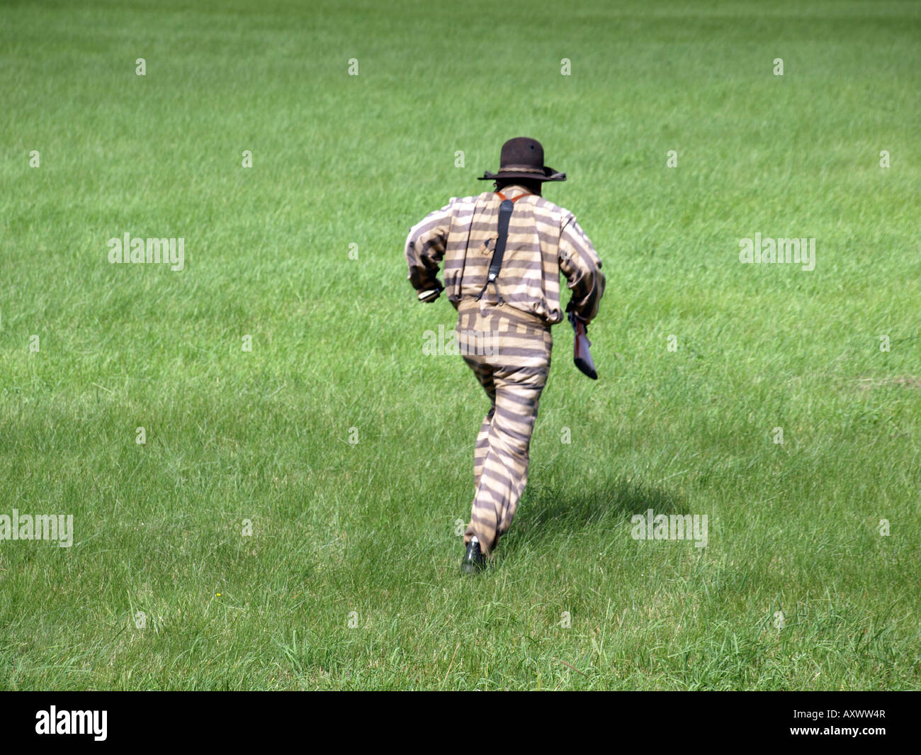 An escapee or excaped convict in jailbird clothing running with a ...